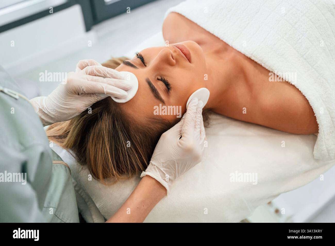 Cotton pad or sponge are used to clean the skin. Woman face getting ...