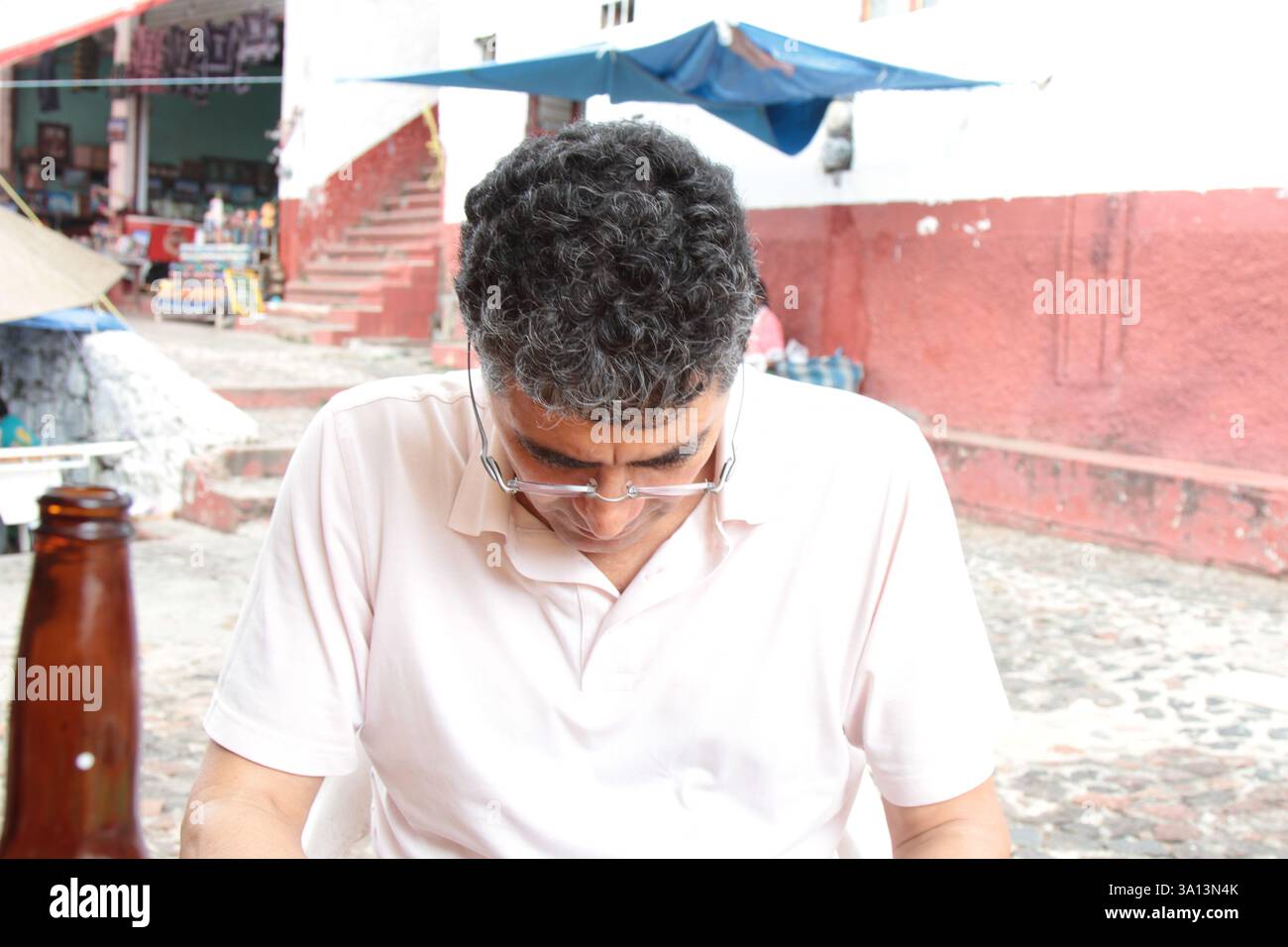 A Mexican man sitting with curly hair looking down on the ground Stock ...