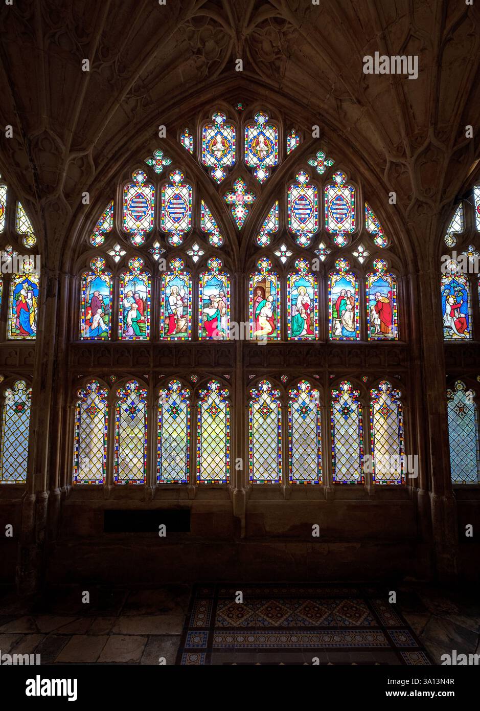 an arched stained glass window in the cloisters at Gloucester Cathedral ...