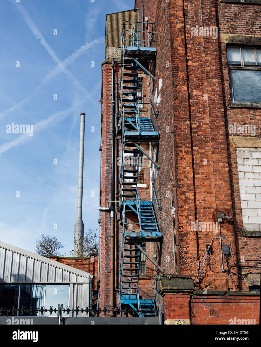 Tall brick building with a blue fire escape. The building is located in ...