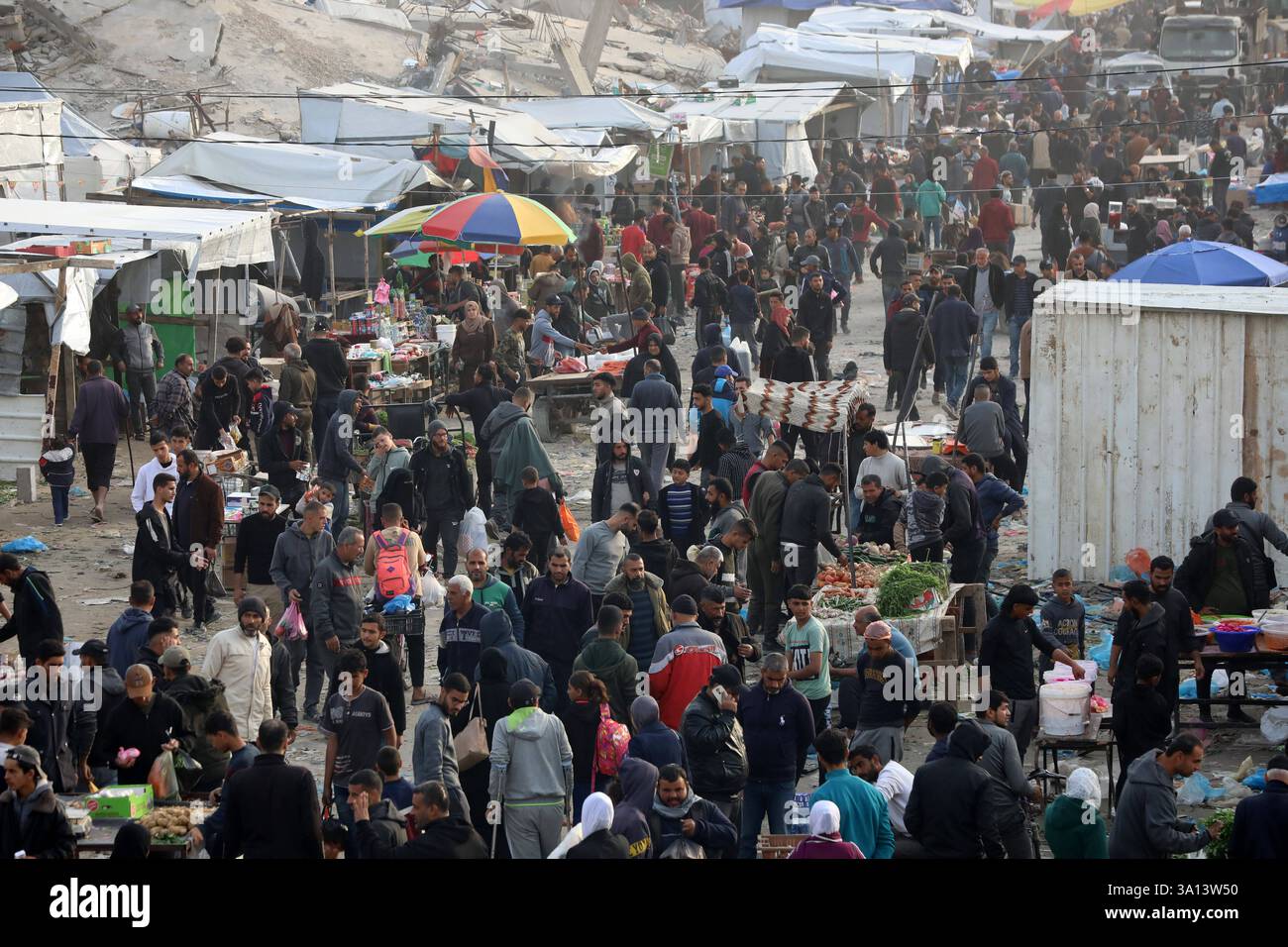 Palestinians shop at a market set up among the rubble in Jabalia ...