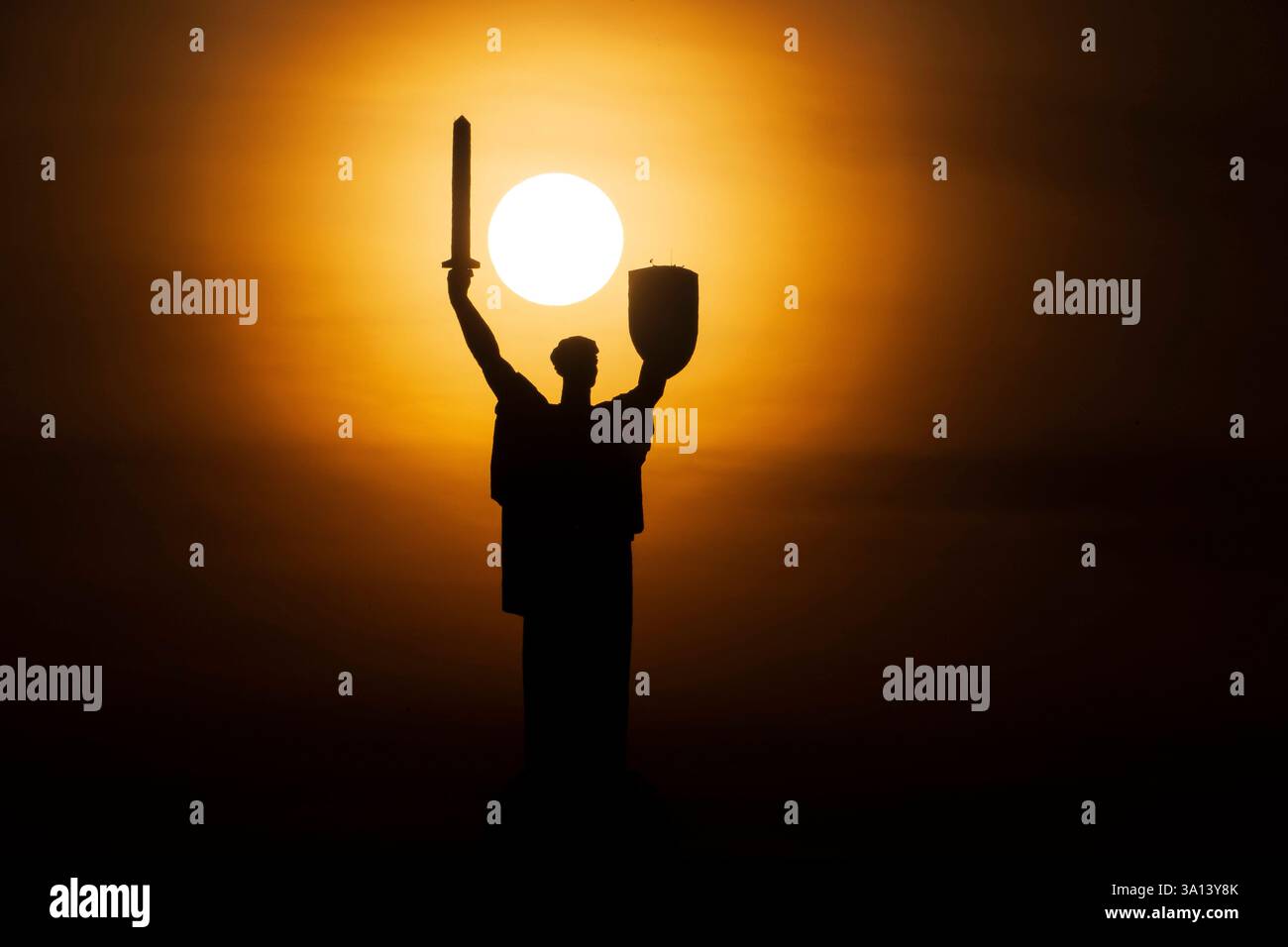 Sun setting behind the Mother Ukraine statue in Kyiv. The sculpture is ...