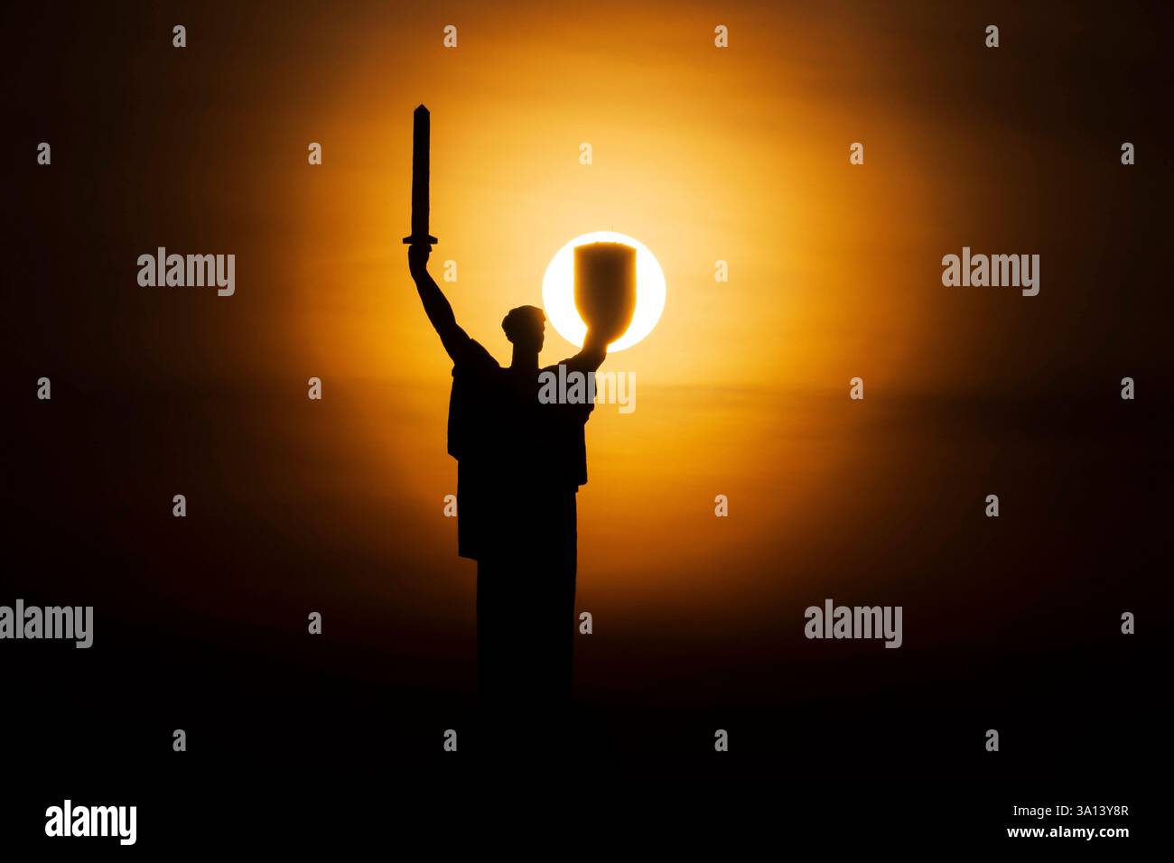 Sun setting behind the Mother Ukraine statue in Kyiv. The sculpture is ...