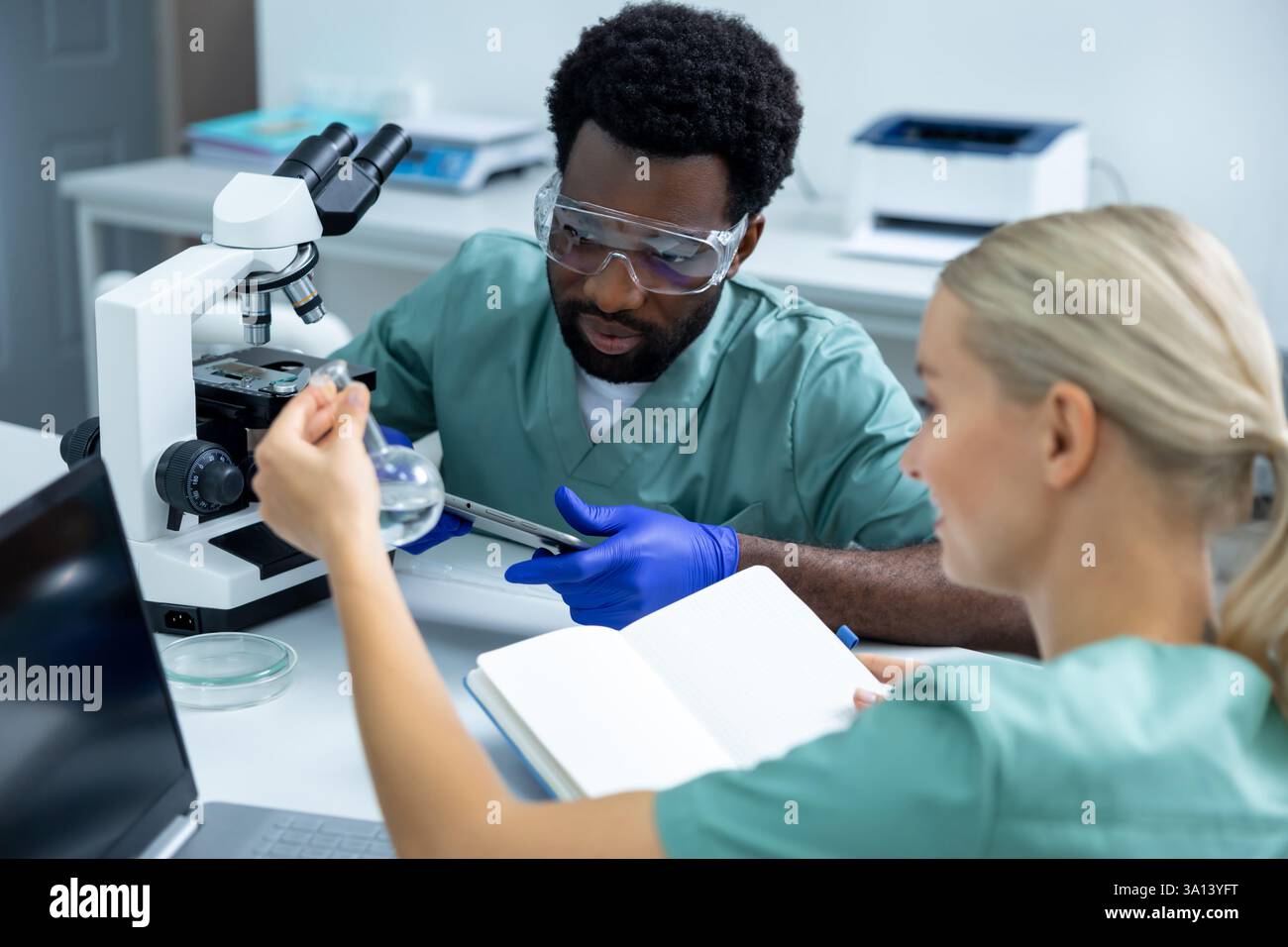 Female and male scientists analyzing DNA samples using microscope and laptop in laboratory Stock ...