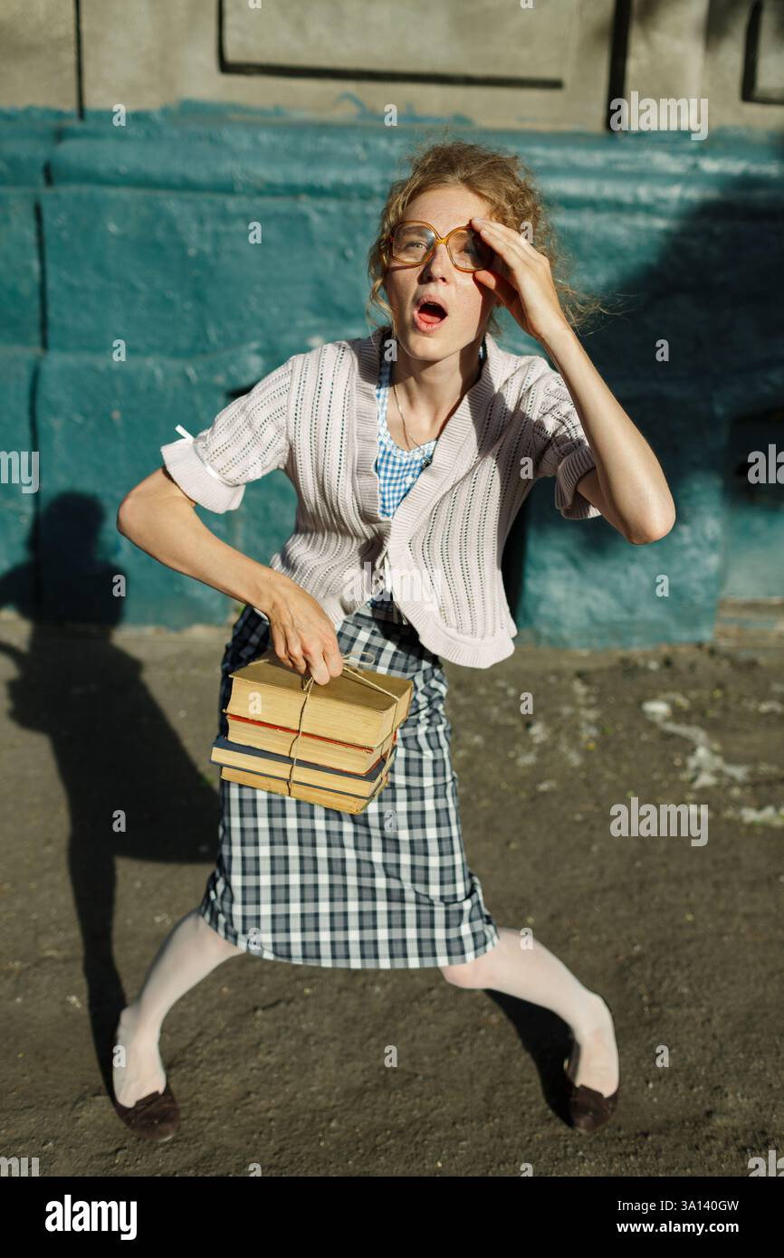 Nerdy young woman in oversized glasses struggles to carry heavy books ...