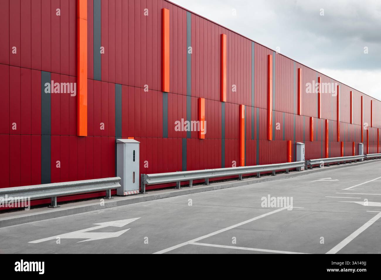 Empty parking lot near red building wall. Concrete parking lot with ...