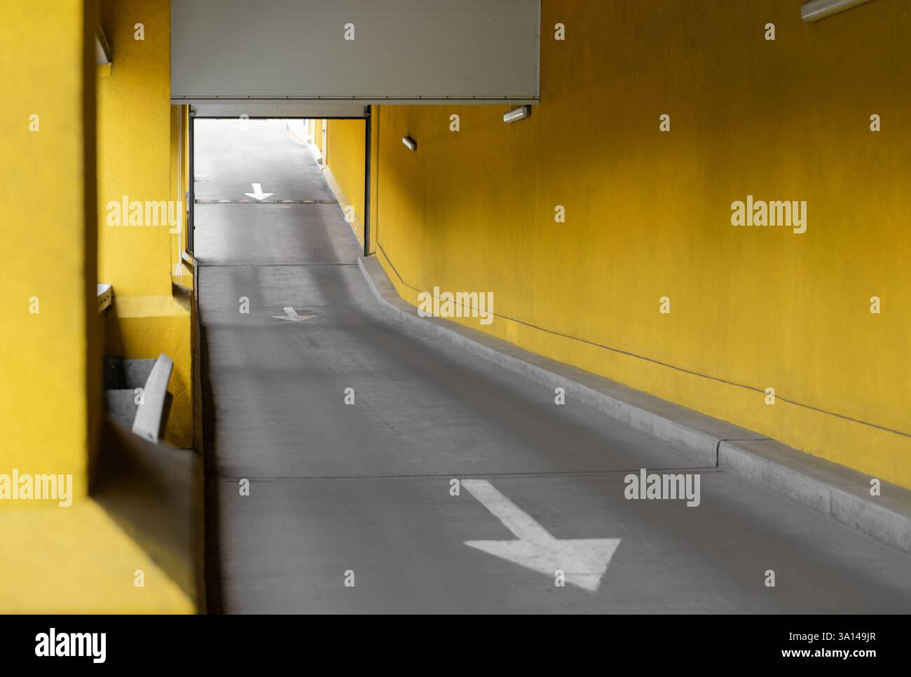 Empty driveway in parking garage. Narrow on-ramp with yellow walls ...