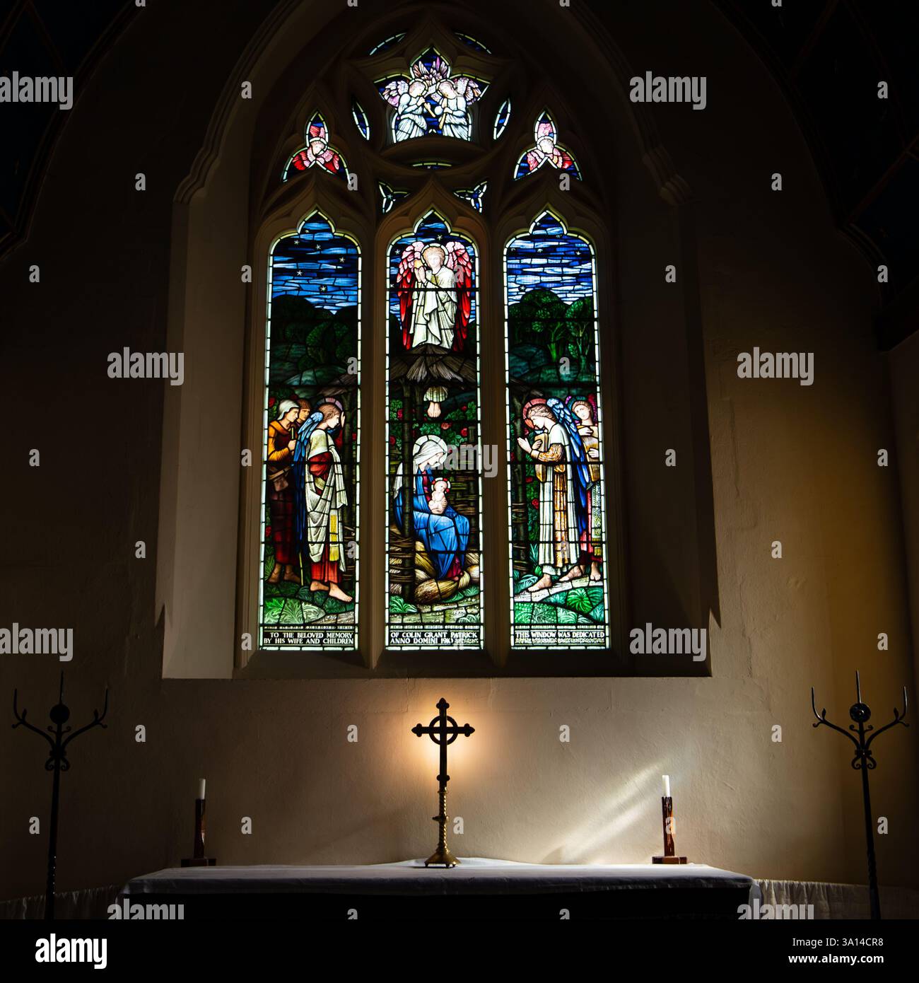 Illuminated stained glass windows above an altar with a cross and ...