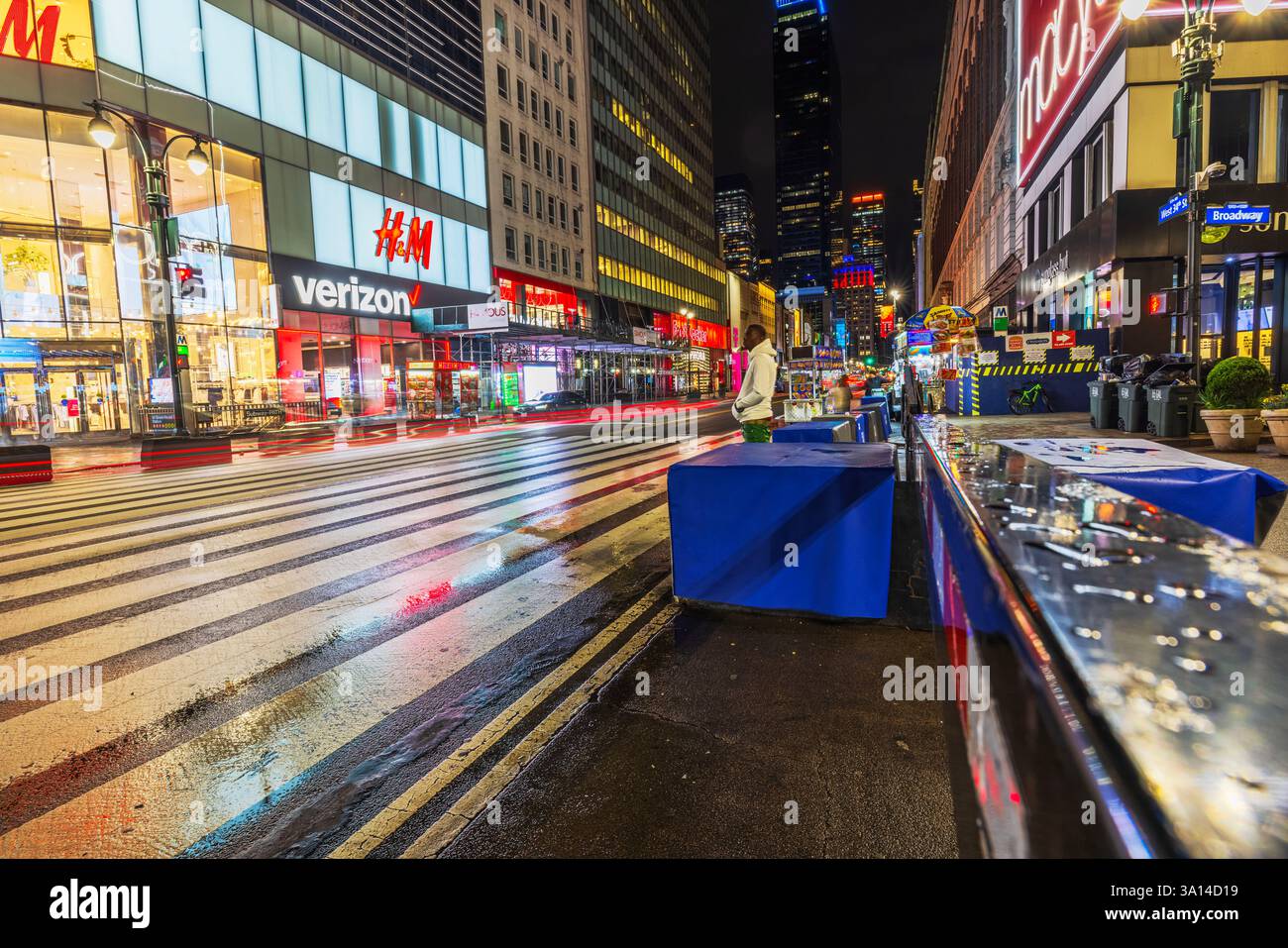 Night view of 34th Street in New York City with bright lights, wet ...