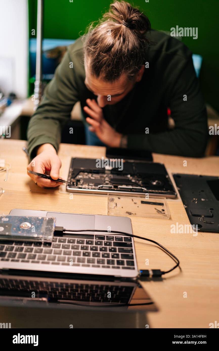 Vertical portrait of technician using tweezers repairing laptop ...