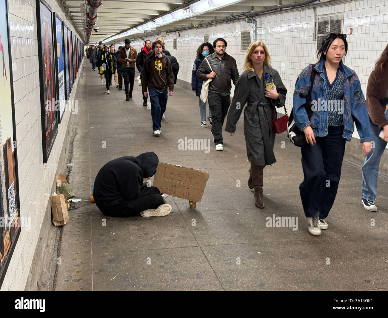 Subway riders pass by a very depressed homeless man Stock Photo - Alamy