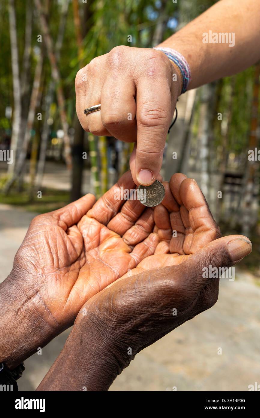 Close-up of hands, one giving money to the other hand of a homeless man ...