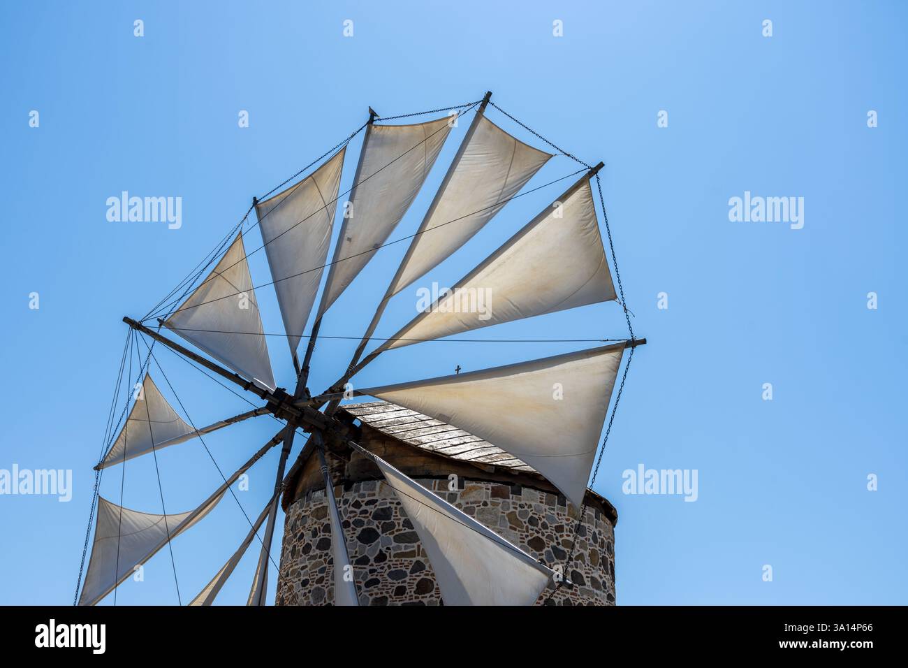 Traditional Greek windmill still working with white sails against blue ...
