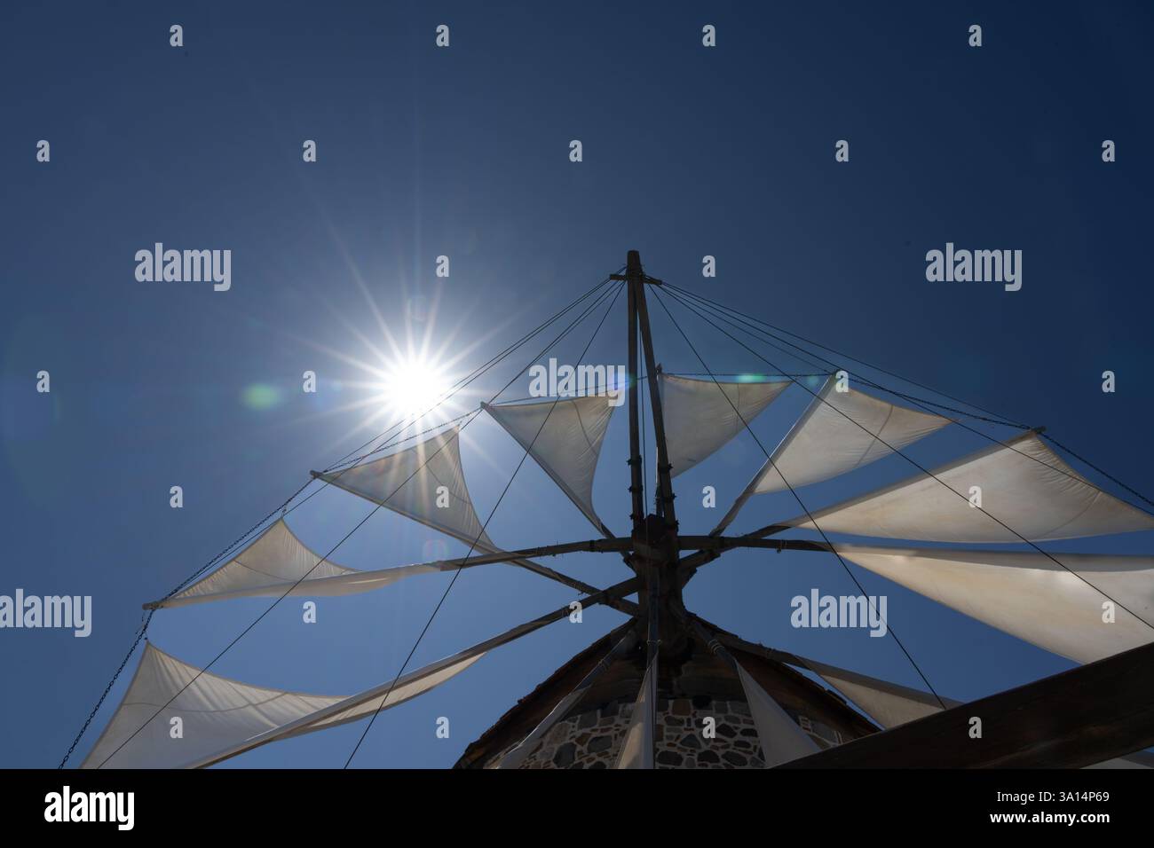 Traditional Greek windmill still working with white sails against blue ...