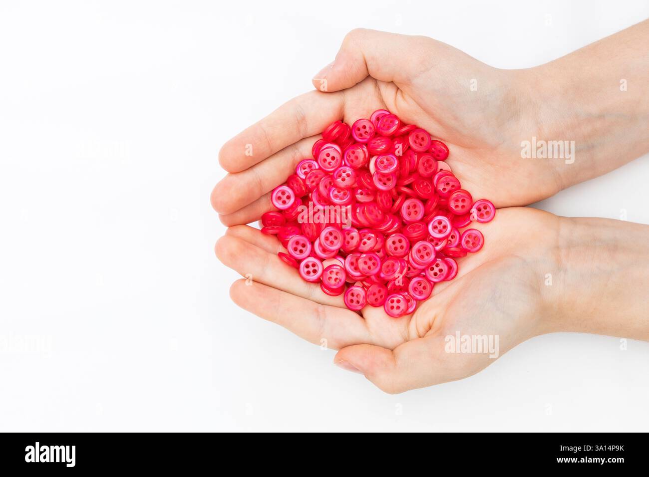 Handful of red buttonhole buttons in the hands Stock Photo - Alamy