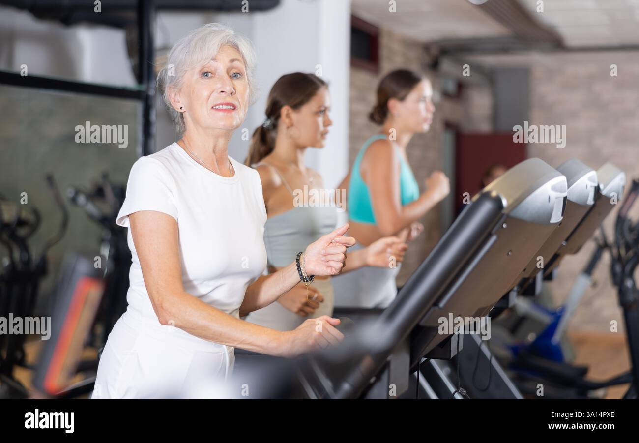 Mature woman running on treadmill in modern fitness club Stock Photo ...