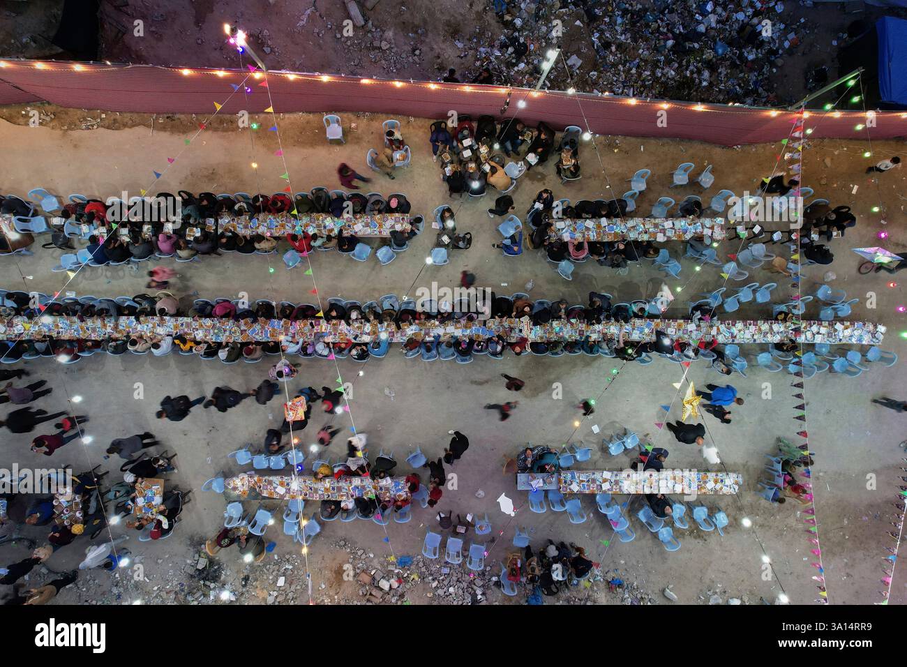 Palestinians sit at a large table as they gather for Iftar, the fast ...