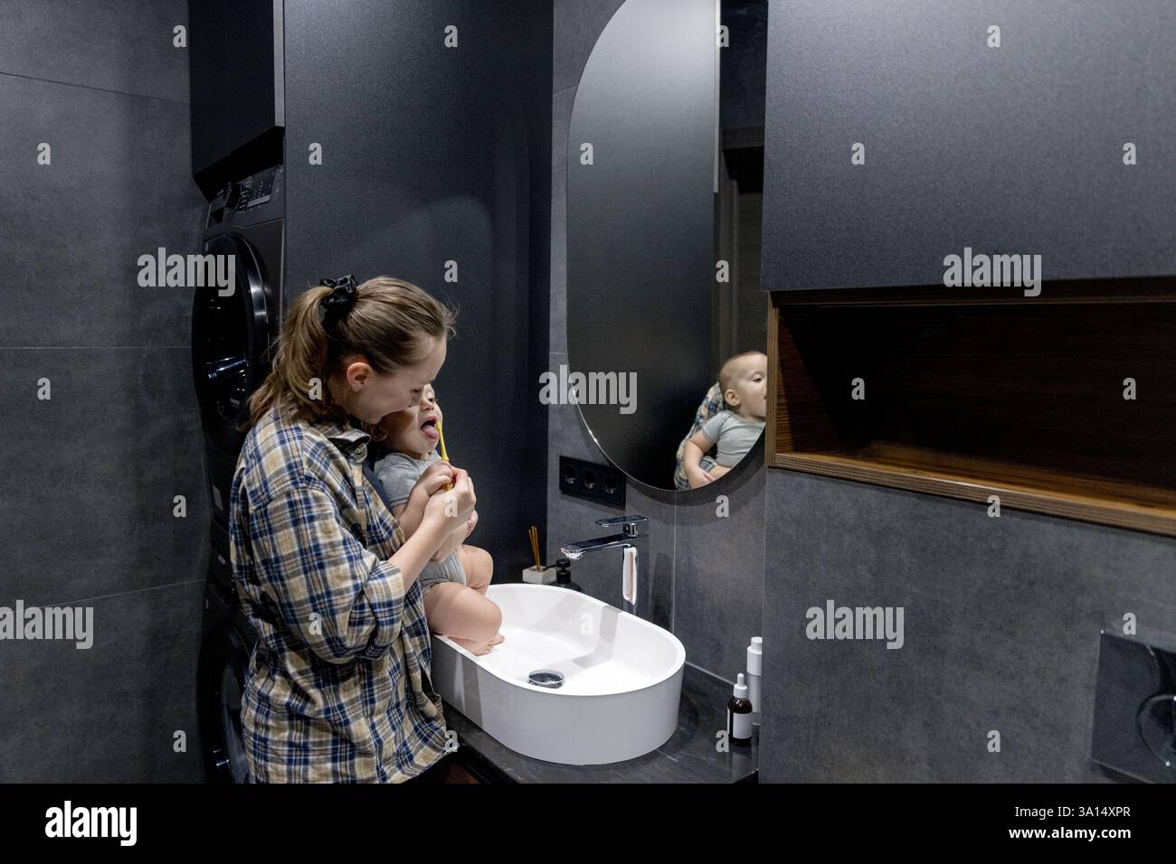 A woman is diligently brushing her teeth while simultaneously holding a ...