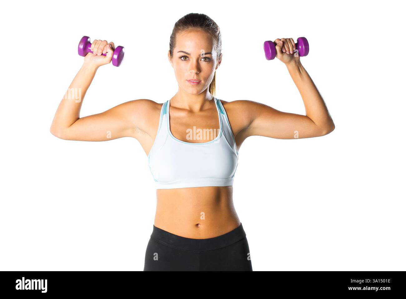A beautiful brunette fitness model poses confidently in a studio, showcasing her toned muscles ...