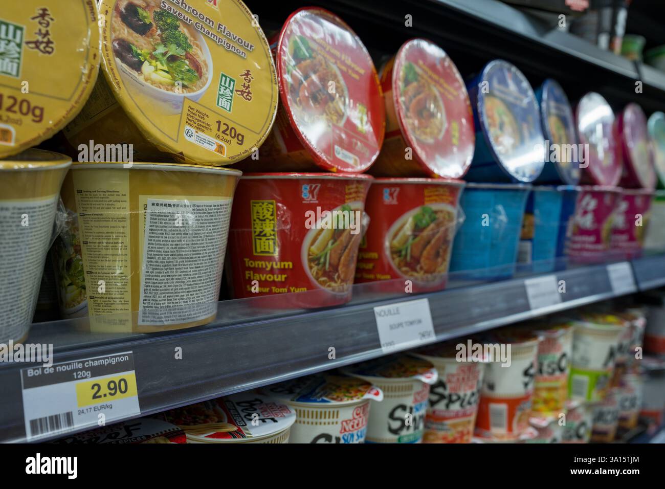 Colorful instant noodle cups line the shelves in a bustling grocery ...
