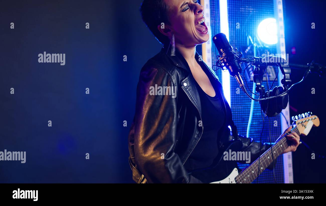 Female musician plays an electric guitar and singing on microphone ...