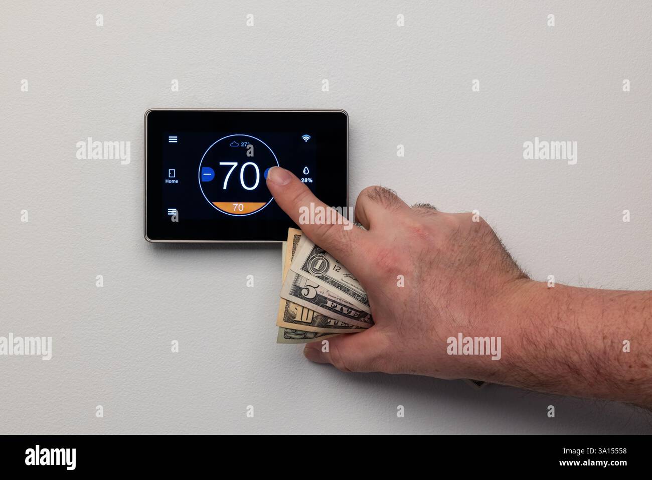 Heating and Cooling Costs - A hand holding money adjusts a touch screen ...