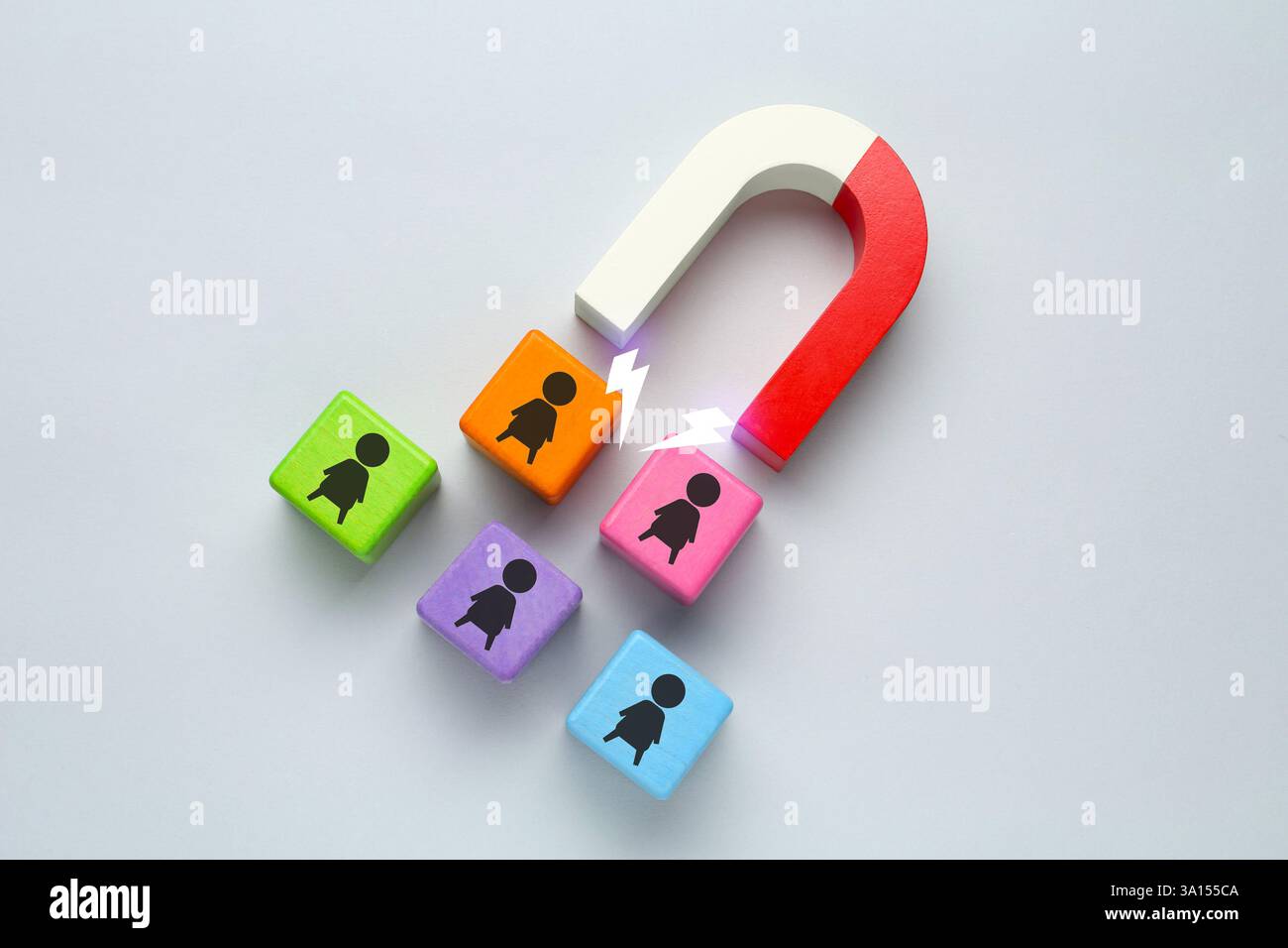 Magnet attracting colorful cubes with human figures on light grey ...