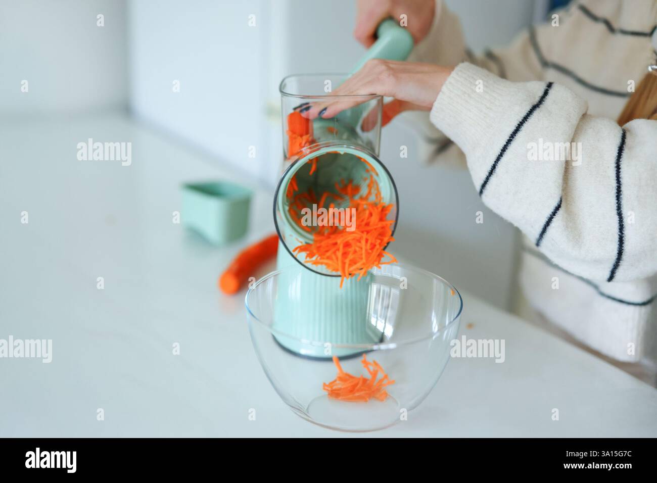 female hand chops carrots on the floor with an automatic blue grater ...
