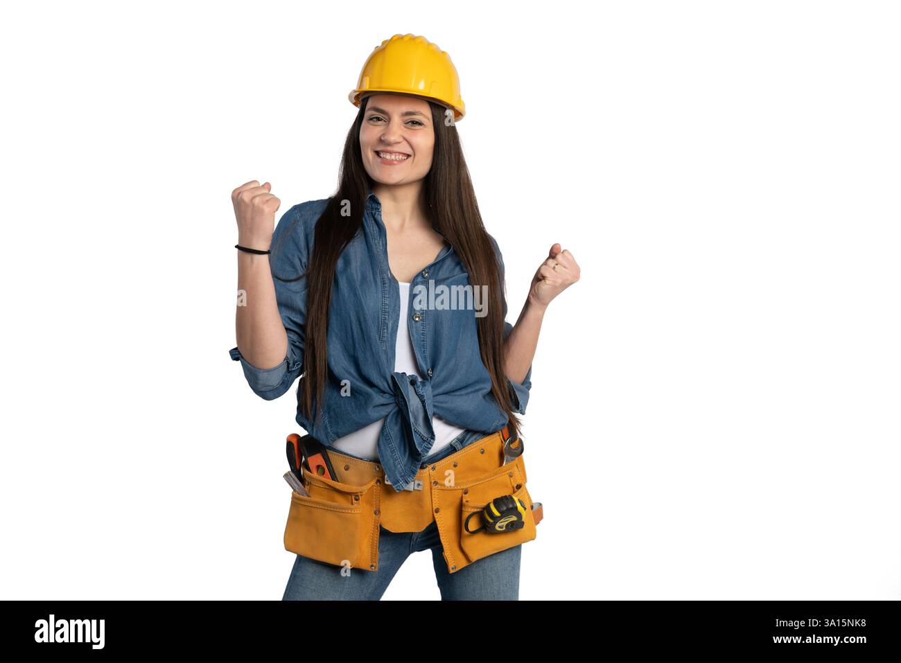 Young female construction worker wearing a yellow hard hat and tool belt, smiling confidently ...