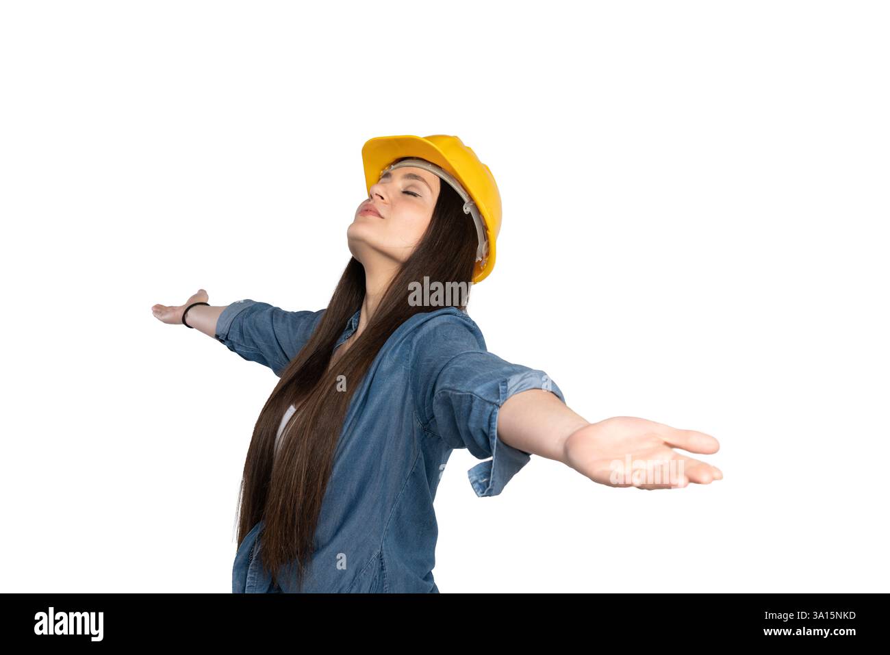 Young female construction worker wearing a yellow hard hat, arms wide open and head tilted back ...