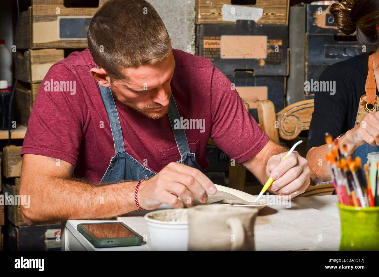 Potter smoothing a clay plate in his workshop using pottery tools Stock ...
