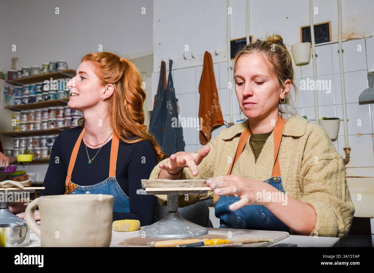Two craftswomen working with clay in pottery workshop, creating ...
