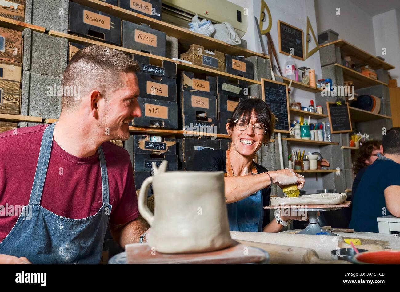 Two smiling craftspeople creating and modeling ceramics in their ...