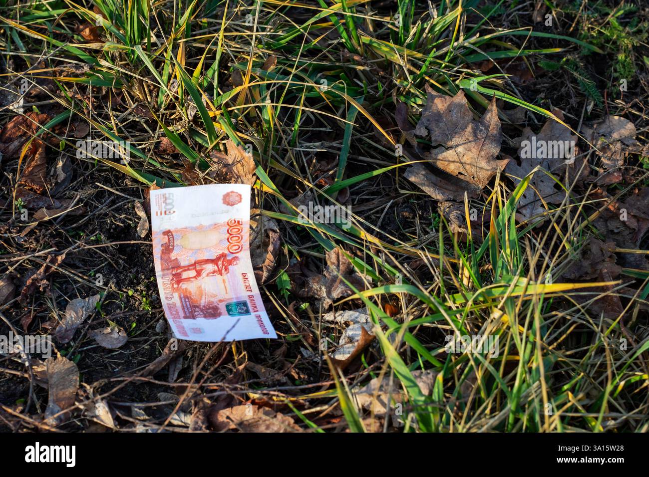 A crumpled Russian ruble bill is carelessly lying on the ground amidst ...