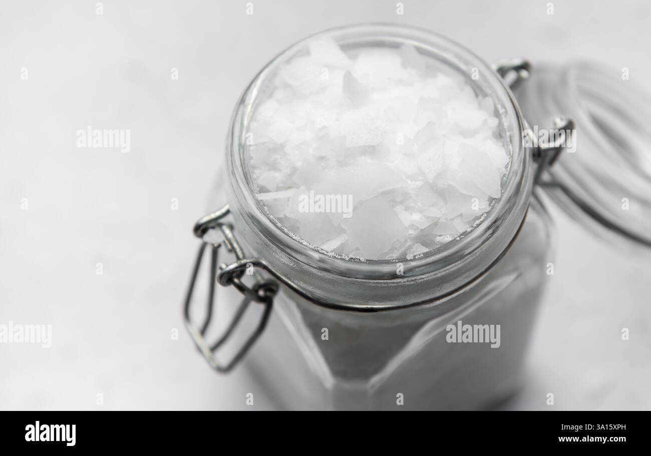 Magnesium chloride flakes are being stored in a glass jar with a metal ...