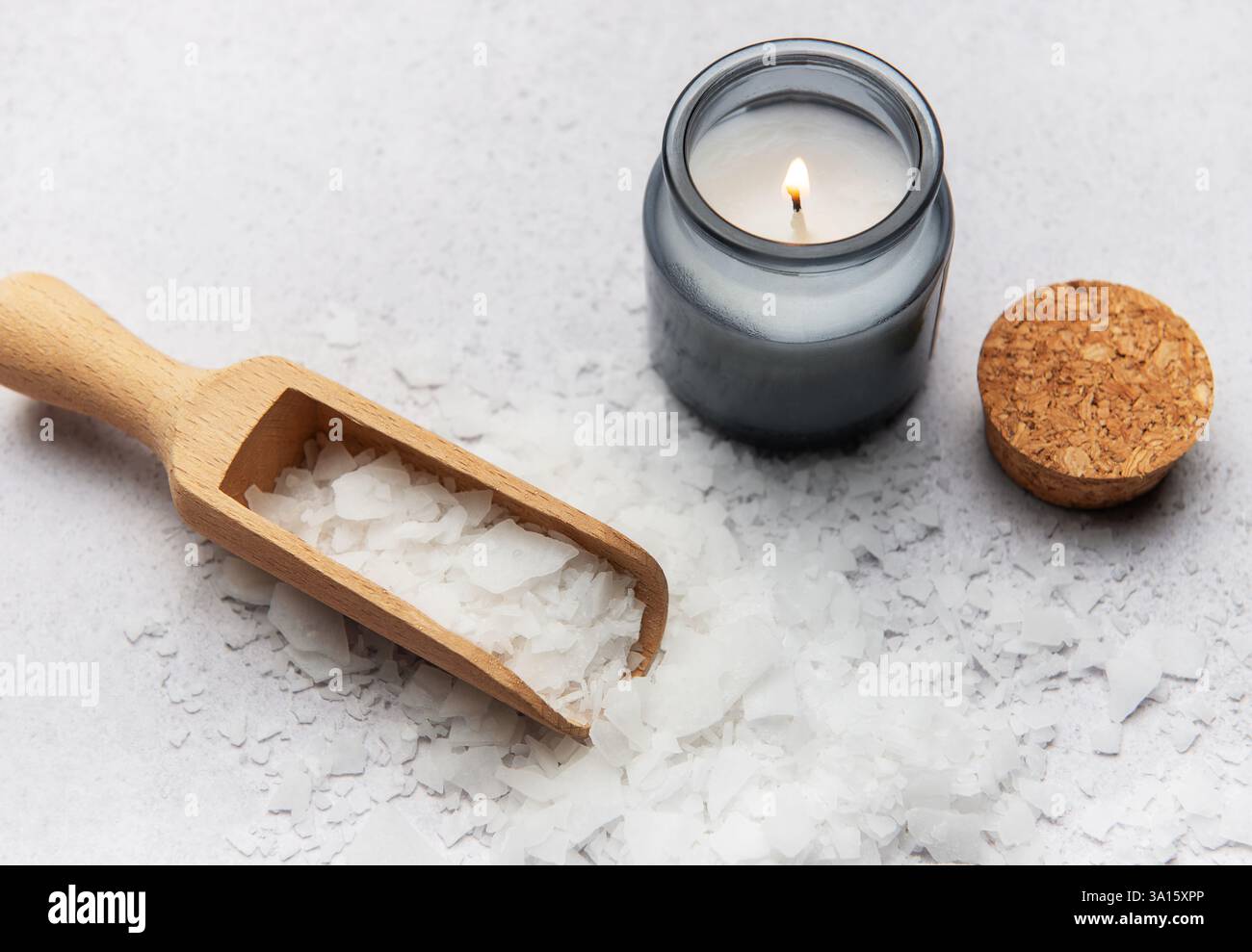 Magnesium bath flakes in wooden scoop with burning candle for relaxing ...