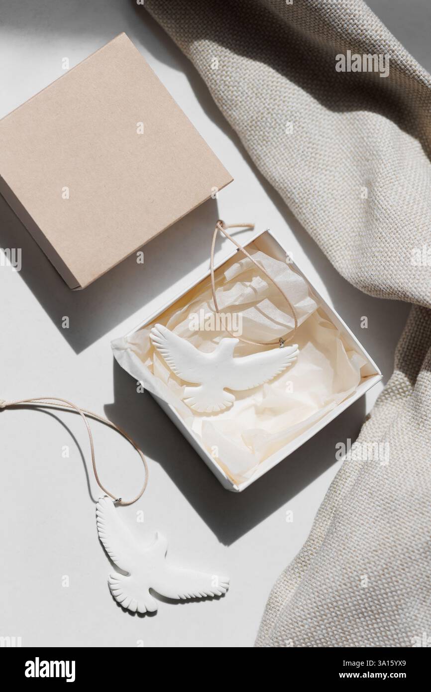 Delicate white bird pendant hung gracefully beside an open gift box on ...