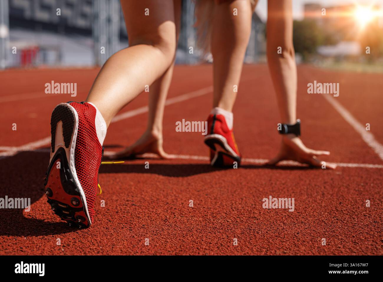Female athlete at the starting line of a sprint race, wearing red track ...