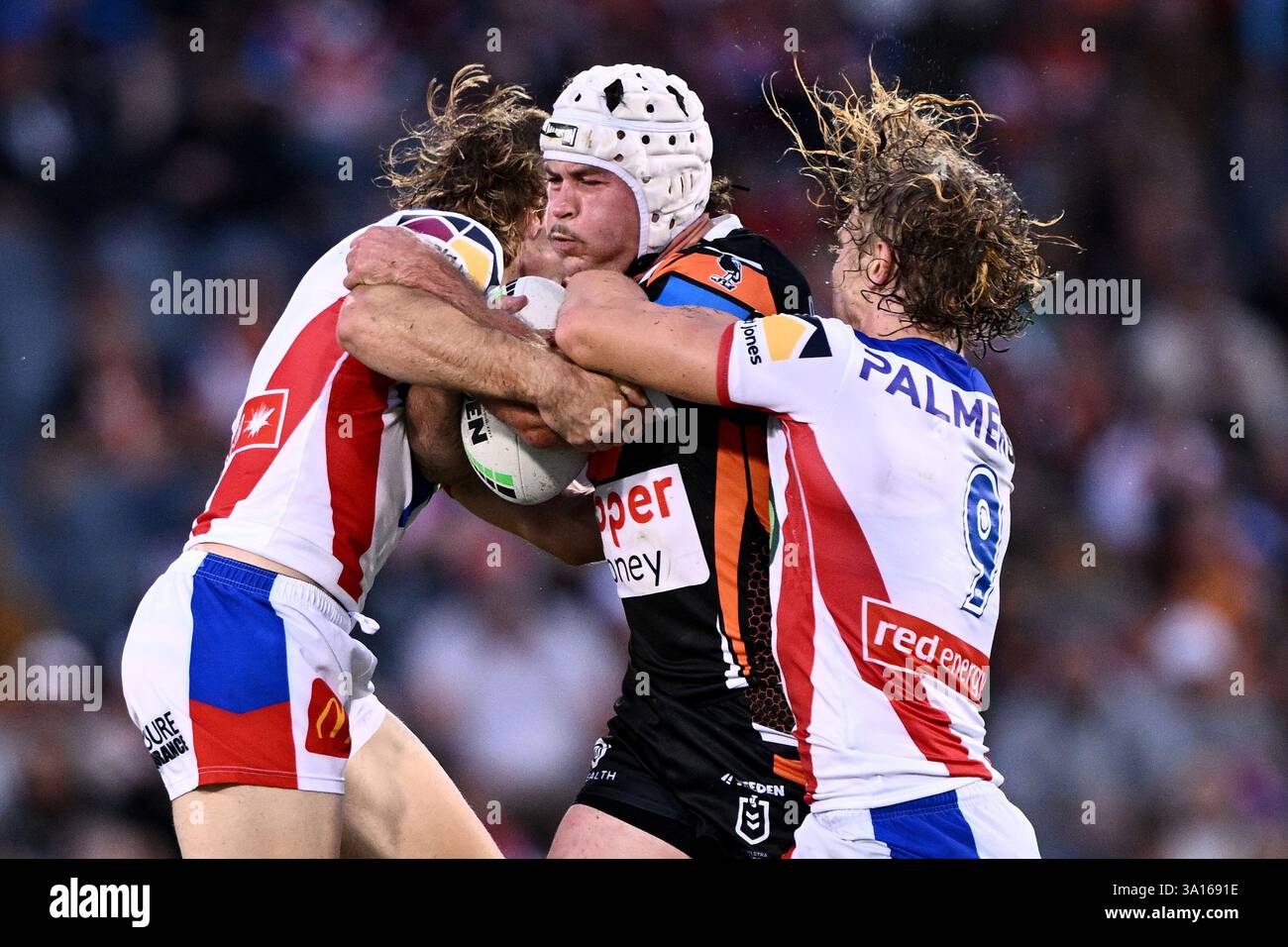 Heath Mason of the Tigers is tackled by Fletcher Sharpe (left) and ...