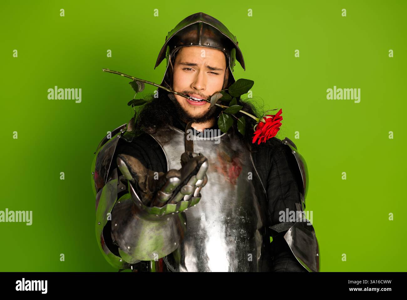 Young man in medieval armor biting rose with a playful expression ...