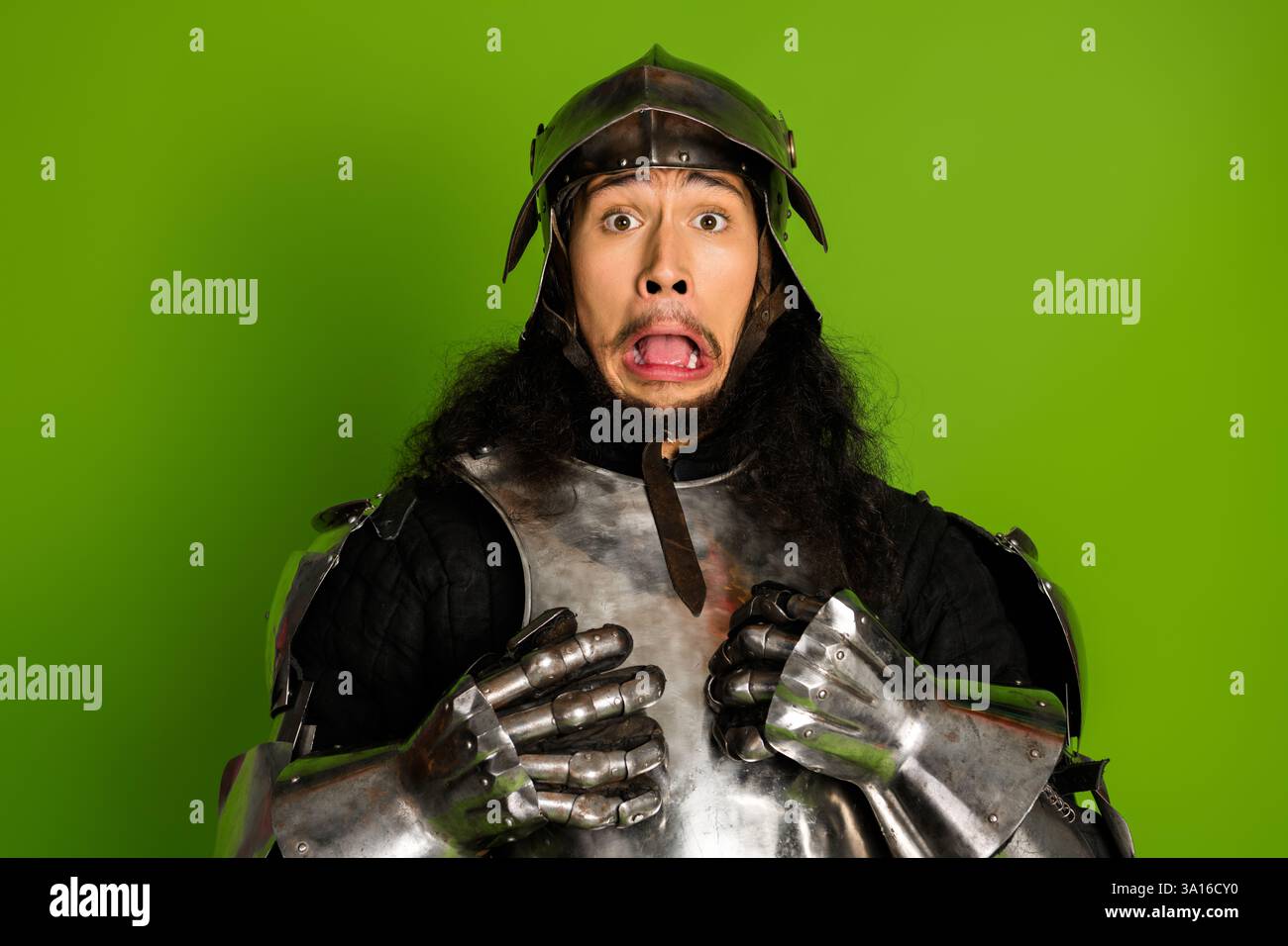 Funny young knight in medieval armor expressing surprise on a bright ...