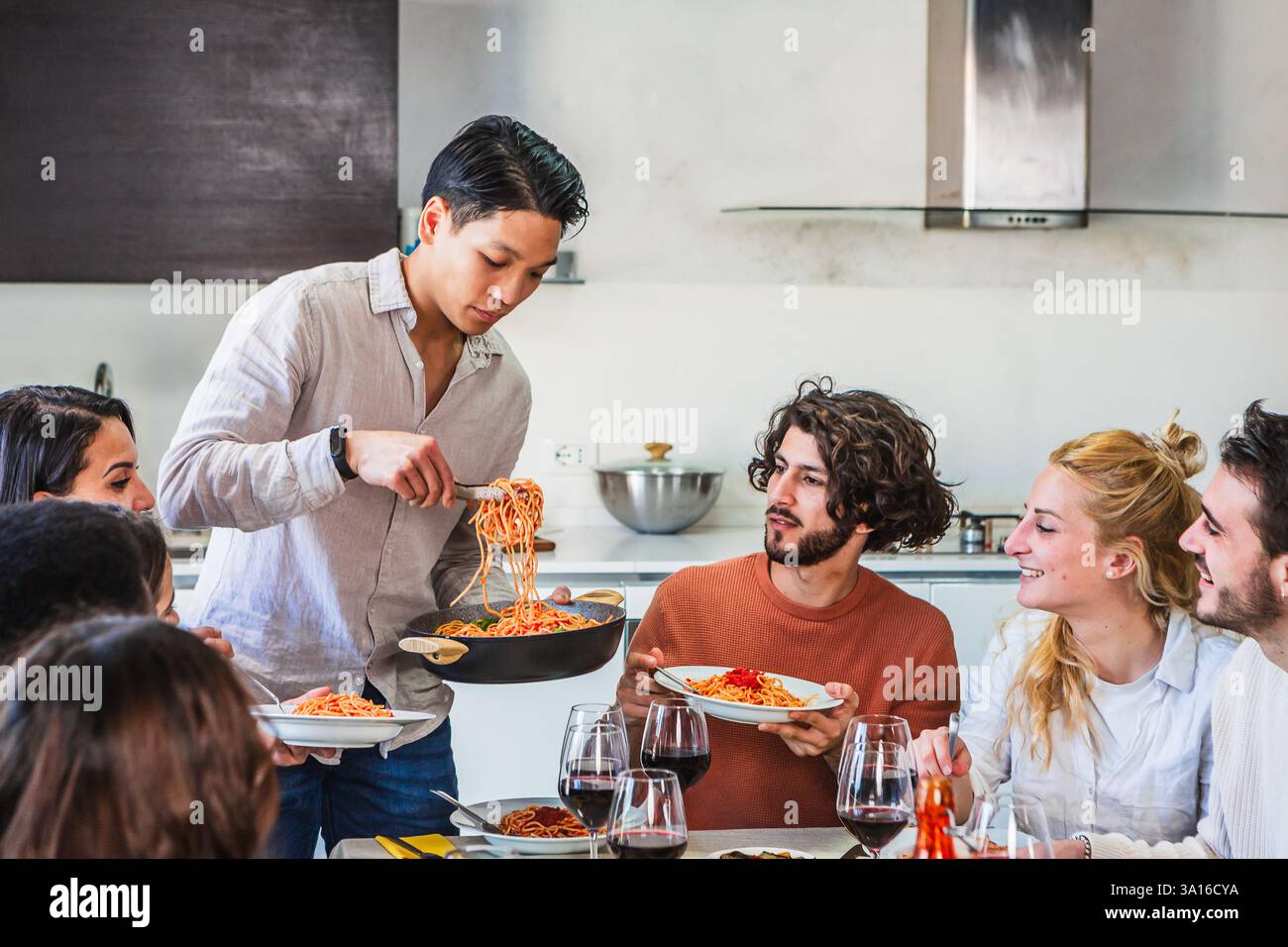 Group of friends enjoying spaghetti and red wine during a convivial ...