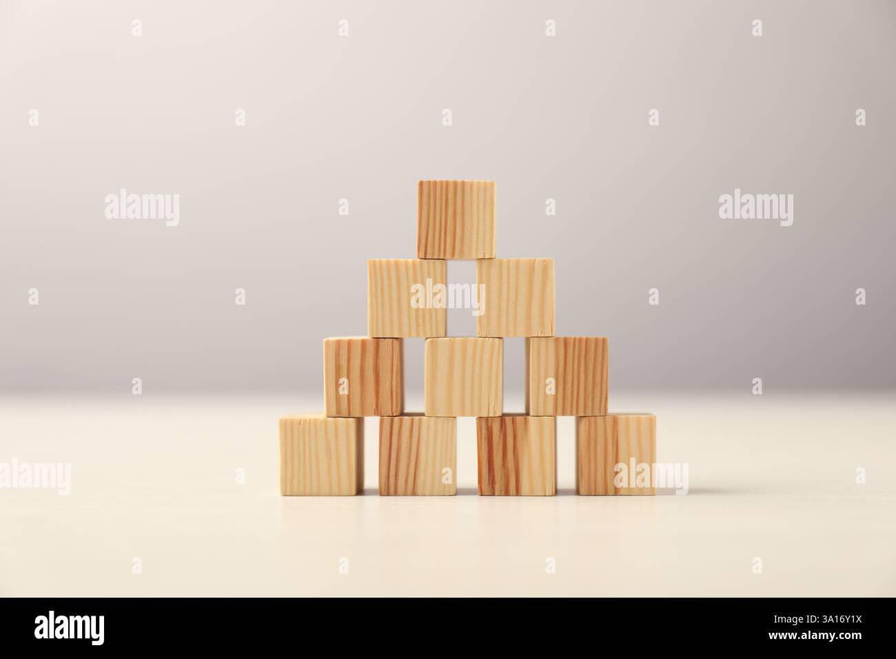 Pyramid of wooden cubes on table against grey background Stock Photo ...