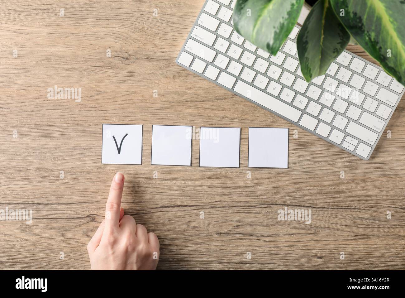 Woman pointing at checkbox with tick mark at wooden table, top view ...
