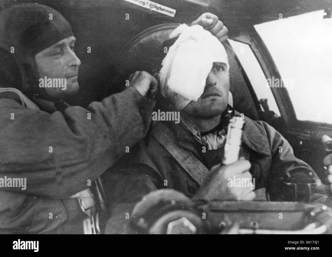 The observer applies a bandage to the wounded pilot of a fighter plane ...