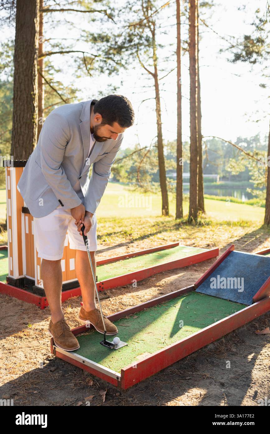 Mini golf player holding golf club next to ball ready to strike Stock ...