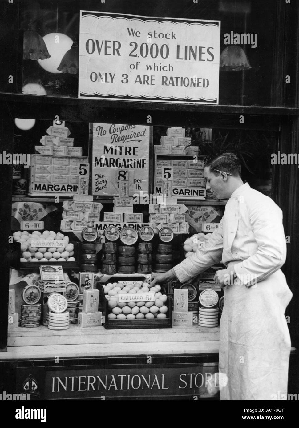 Battle of Britain: A salesman arranges food in the window of a British grocery store. The window ...