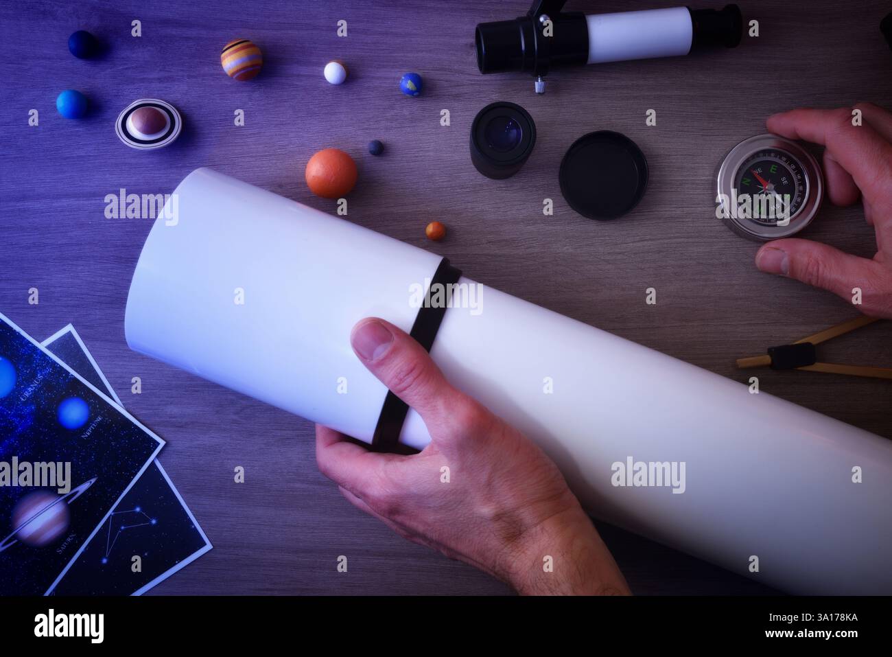 Person with telescope and compass on wooden table with photos and ...