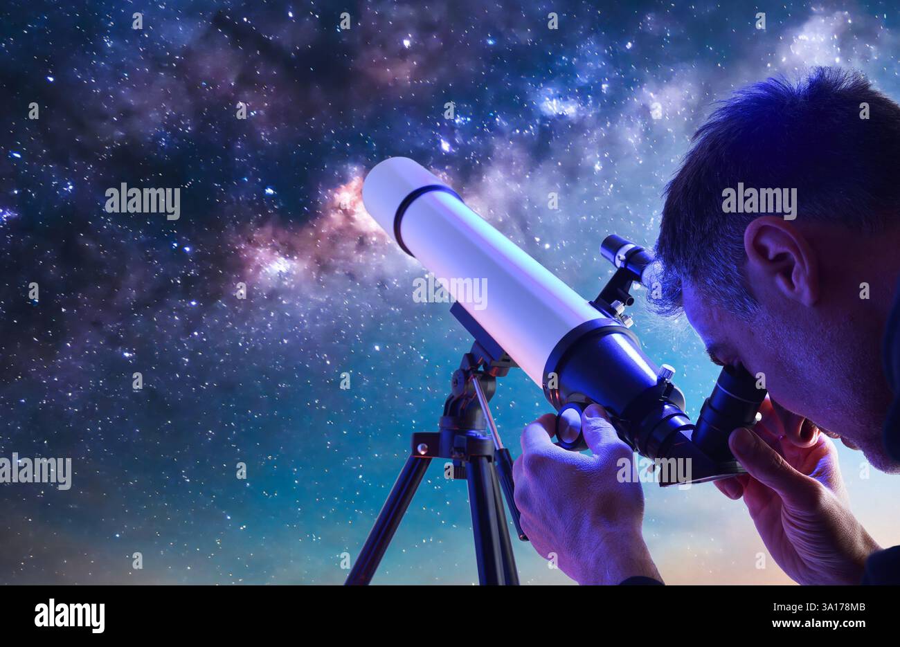 Detail of man outdoors looking through the eyepiece of a telescope ...