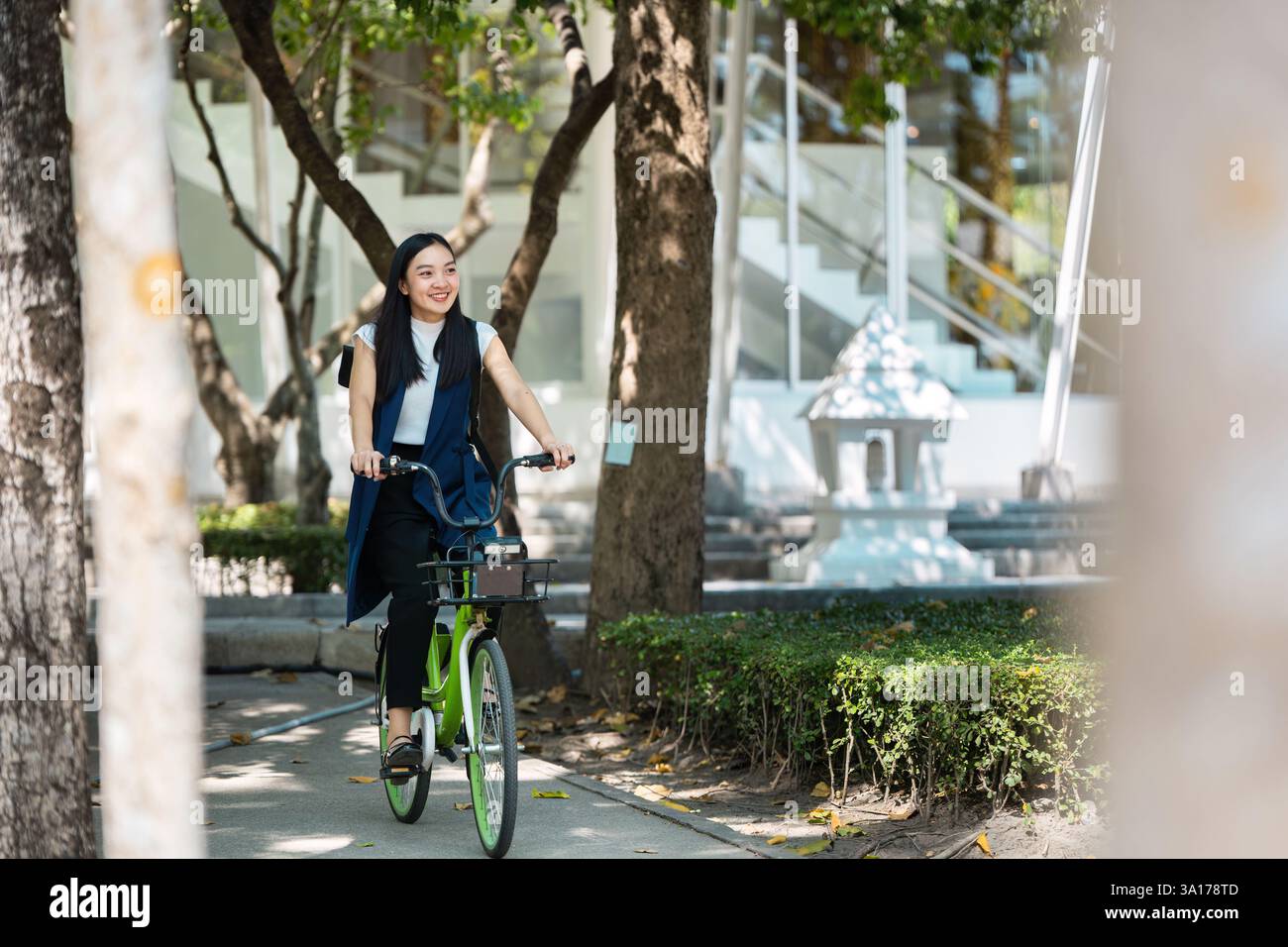 Eco-friendly transportation. Young woman riding a green bicycle through ...